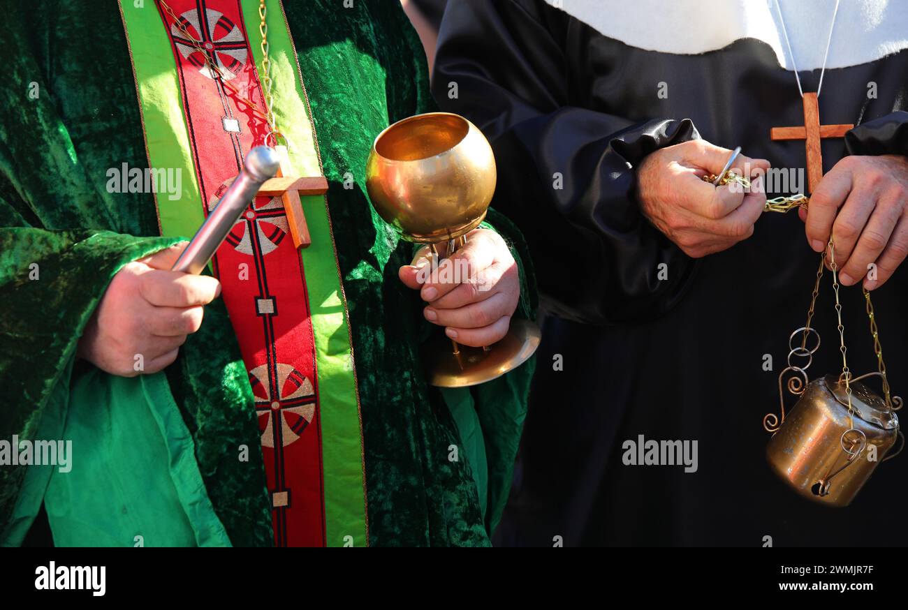 Senior priest with cassock and aspergillum while performing the ...