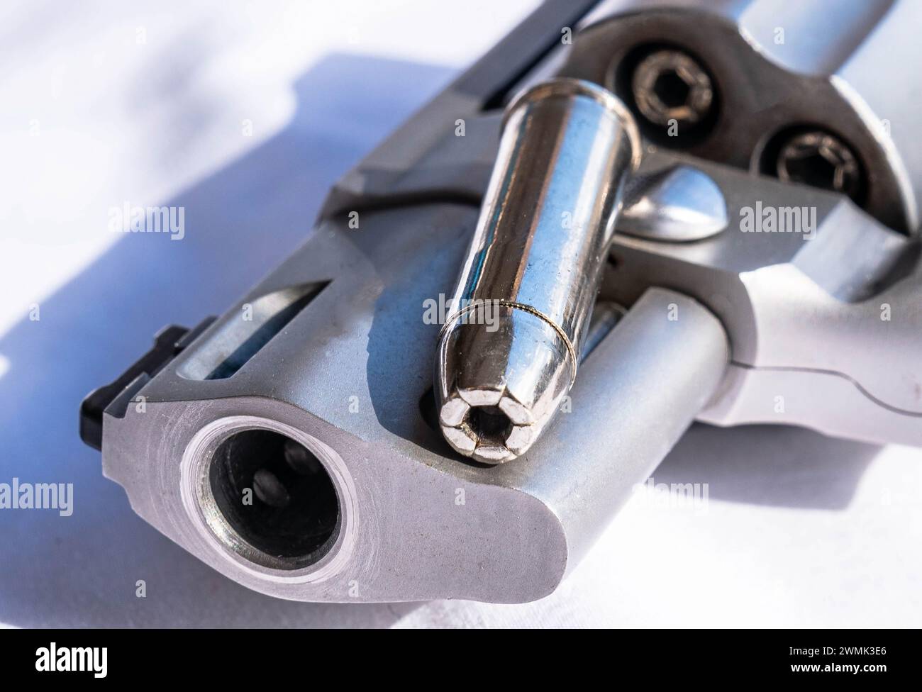 A stainless-steel snub-nosed revolver with a hollow point bullet laid ...