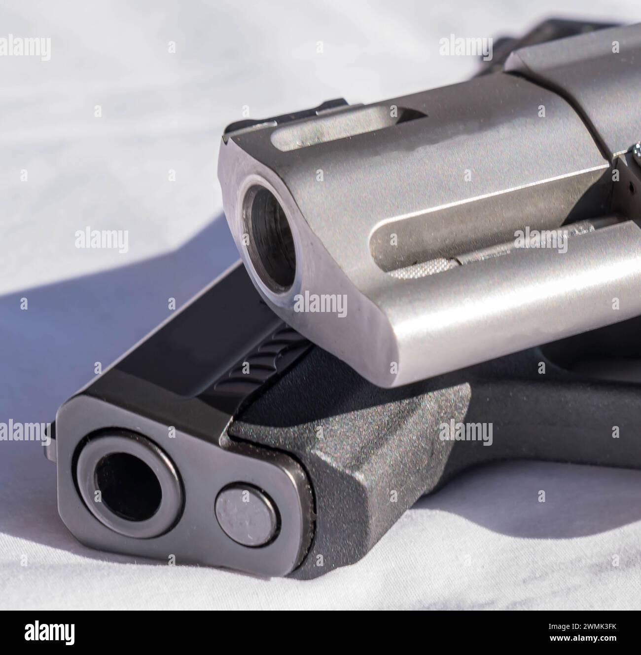 Two handguns, a black pistol and a stainless-steel snub nose revolver ...