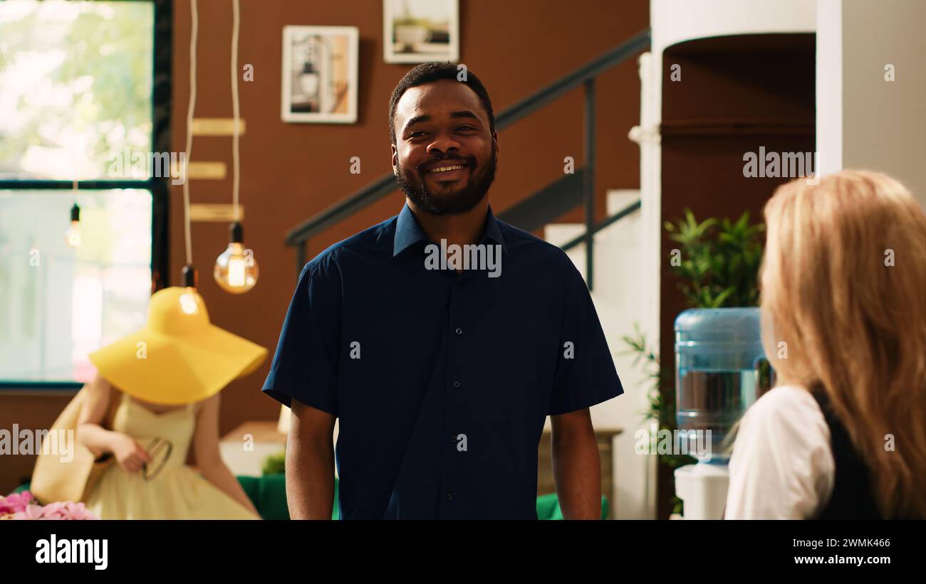 Hotel guest arriving at reception during summertime trip, doing check ...