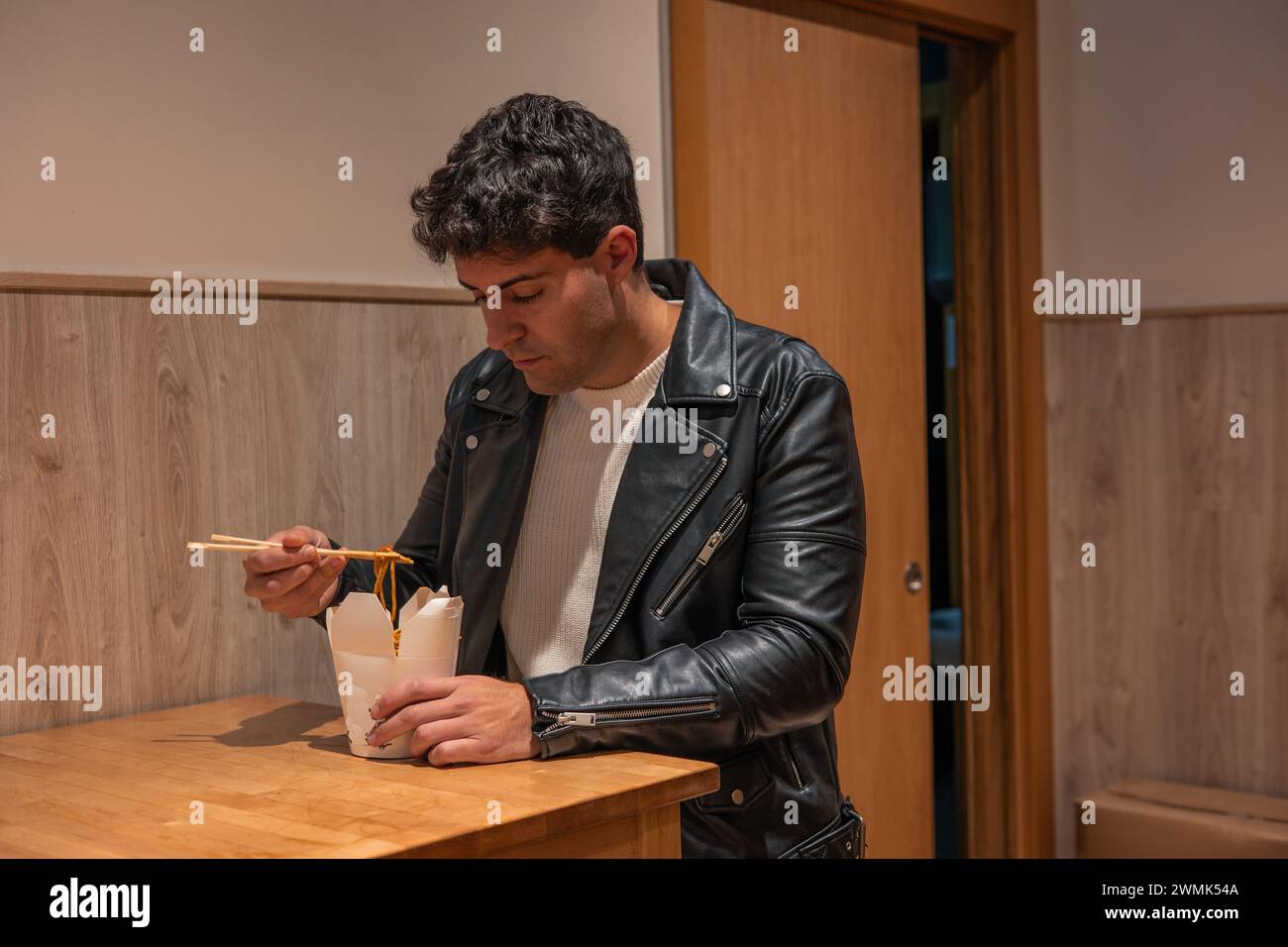 young caucasian man eating chinese noodles fast food wearing leather ...