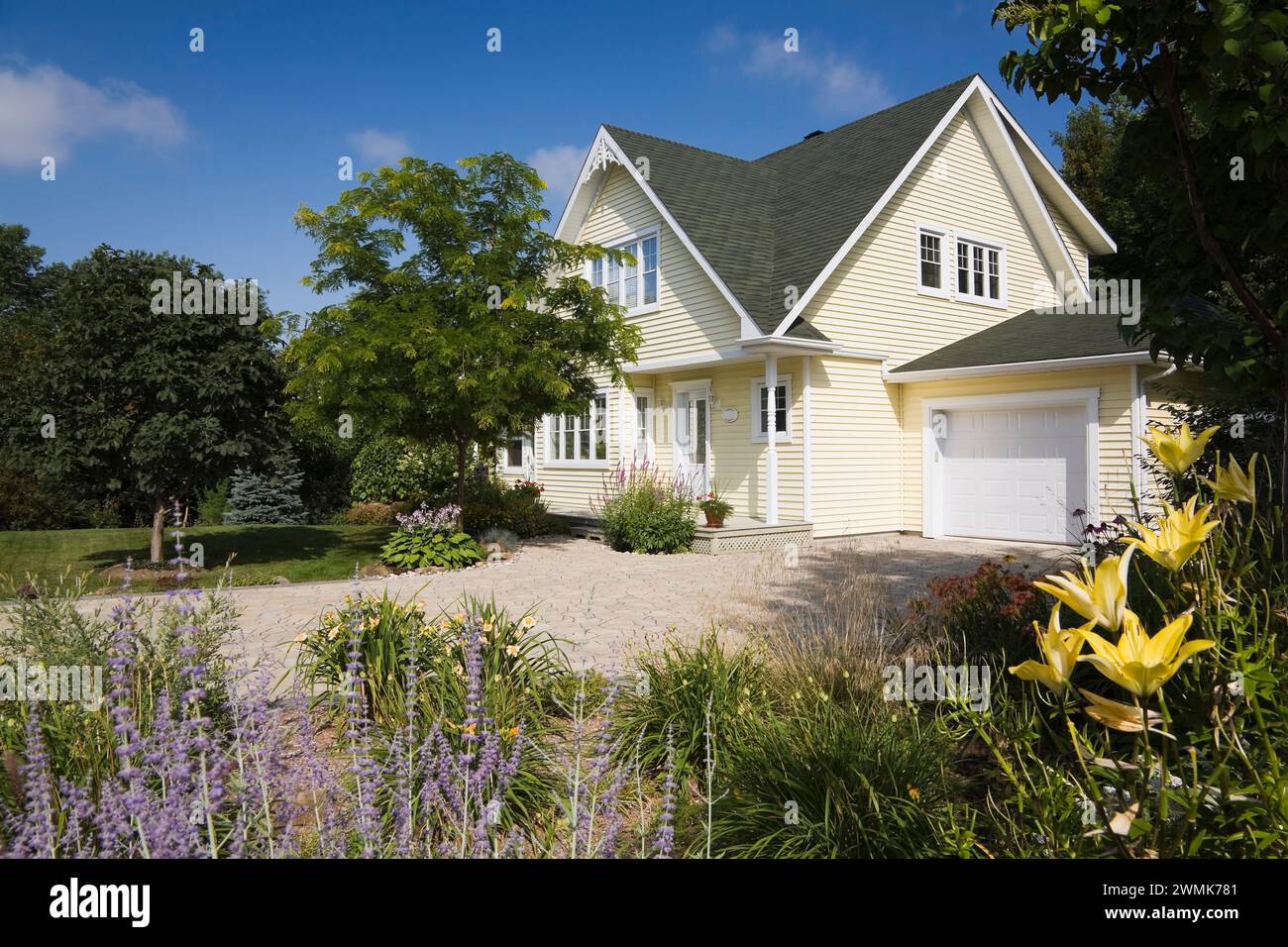 Two storied yellow clapboard with white trim home and landscaped front ...