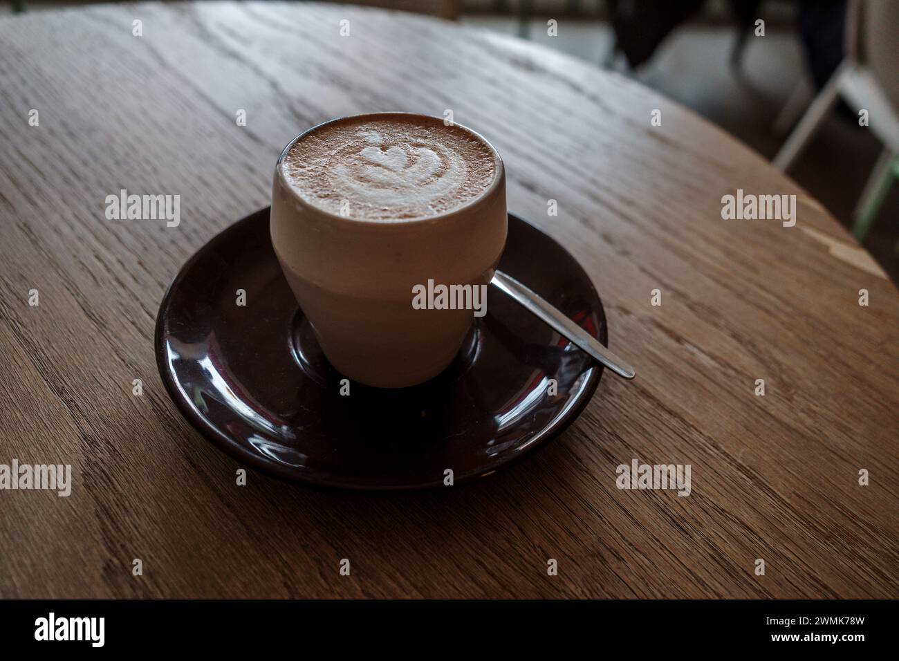 A freshly brewed latte with a heart-shaped art on the foam, sitting on ...