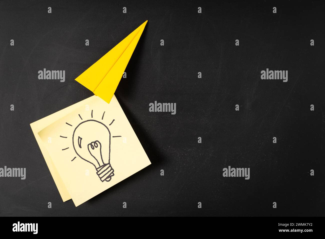 Paper plane carries a hand drawn light bulb symbol on yellow sticky ...
