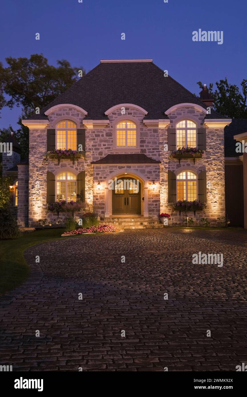 French Manor style natural stone home facade with paving stone driveway ...