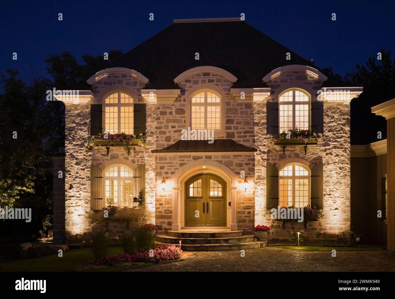 French Manor style natural stone home facade with paving stone driveway ...