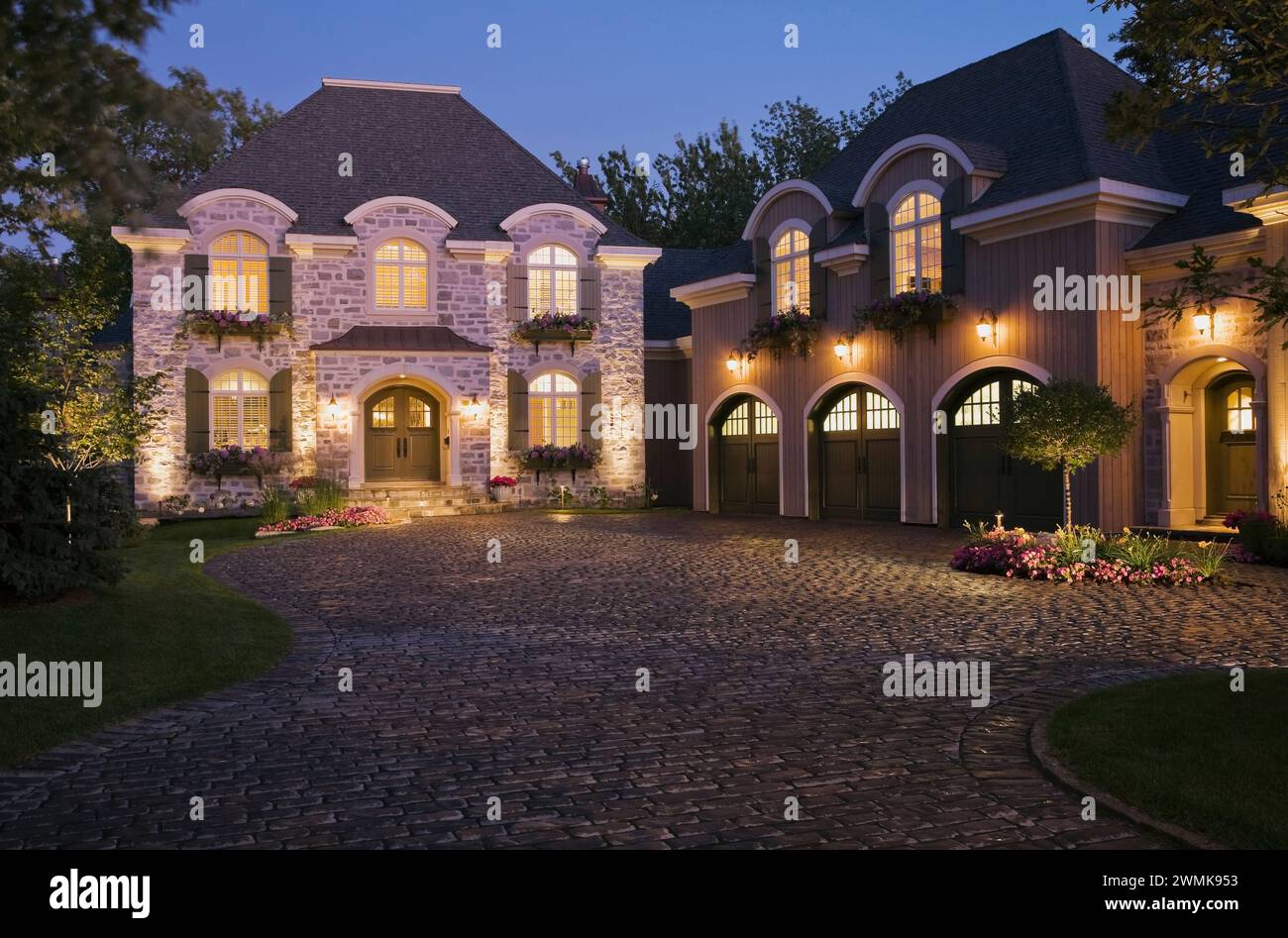 French Manor style natural stone home facade with three car garage and ...