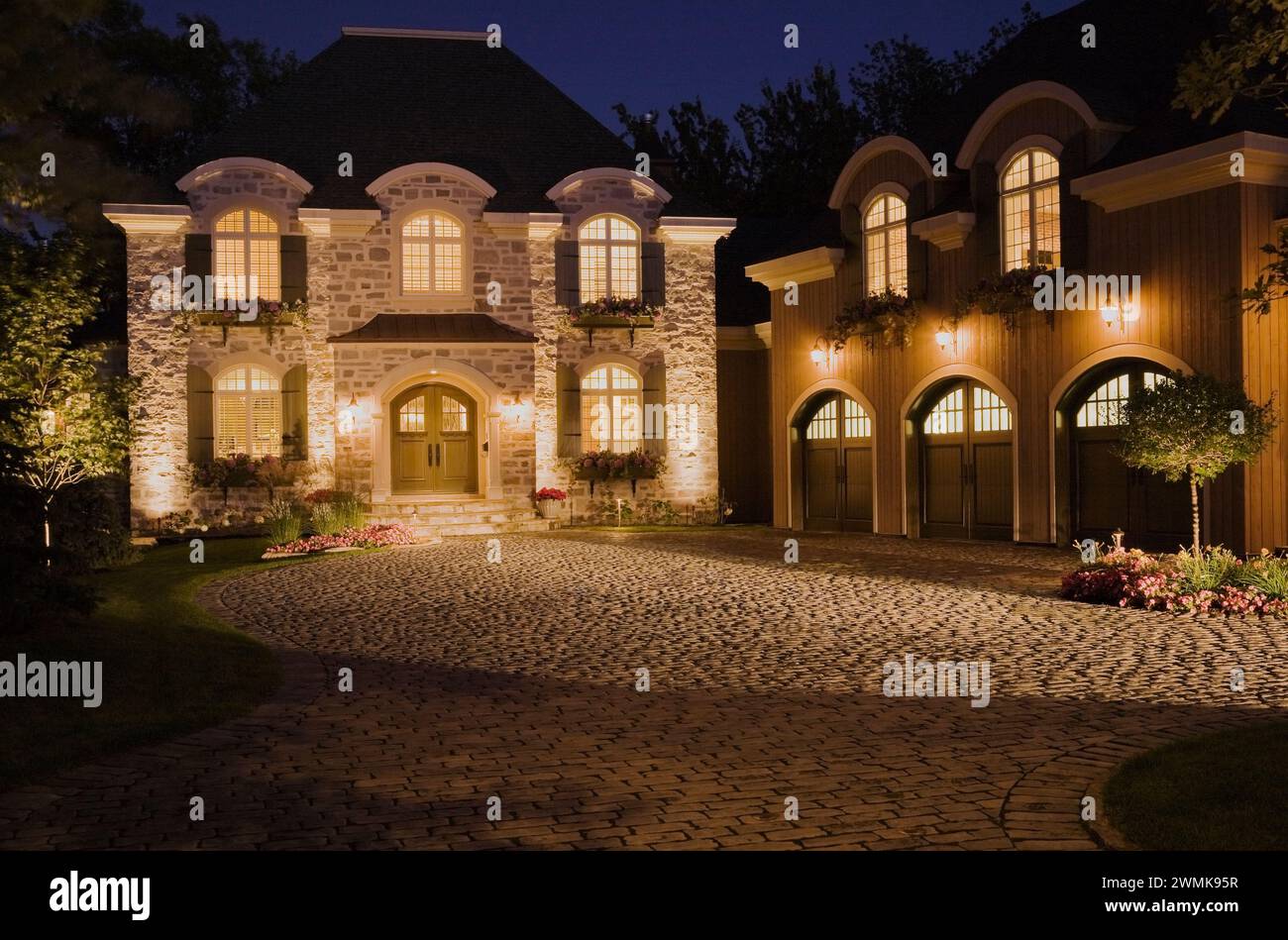 French Manor style natural stone home facade with three car garage and ...