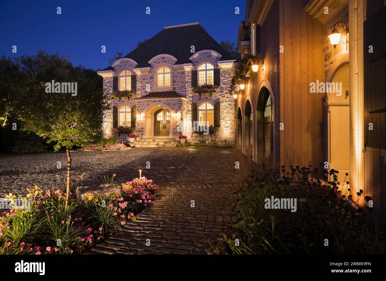 French Manor style natural stone home facade with three car garage and ...