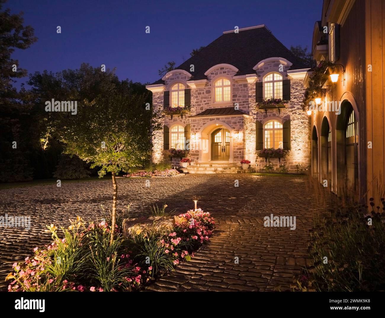 French Manor style natural stone home facade with three car garage and ...