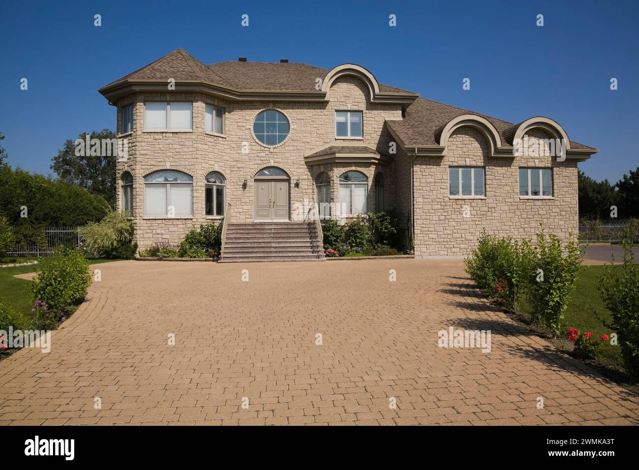 Luxurious two story tan cut stone home with landscaped front yard and ...
