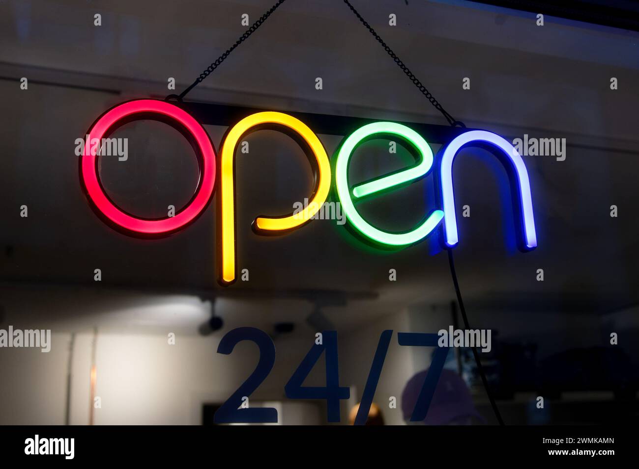 a brightly colored OPEN sign hangs on the window of a clothing store in ...