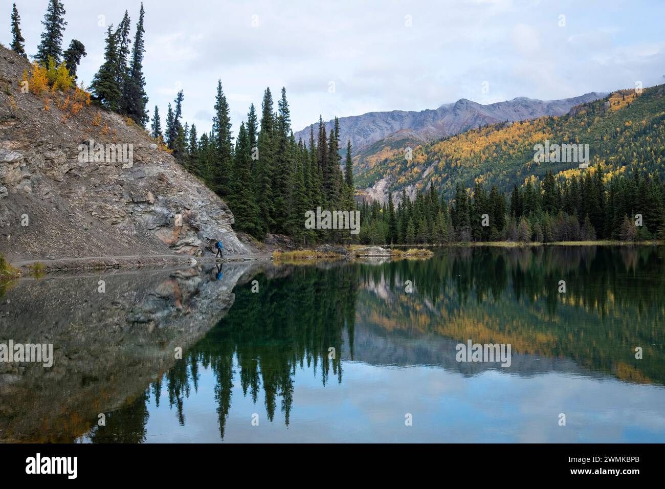 Woman hiking with beautiful reflection of autumn colours along the ...
