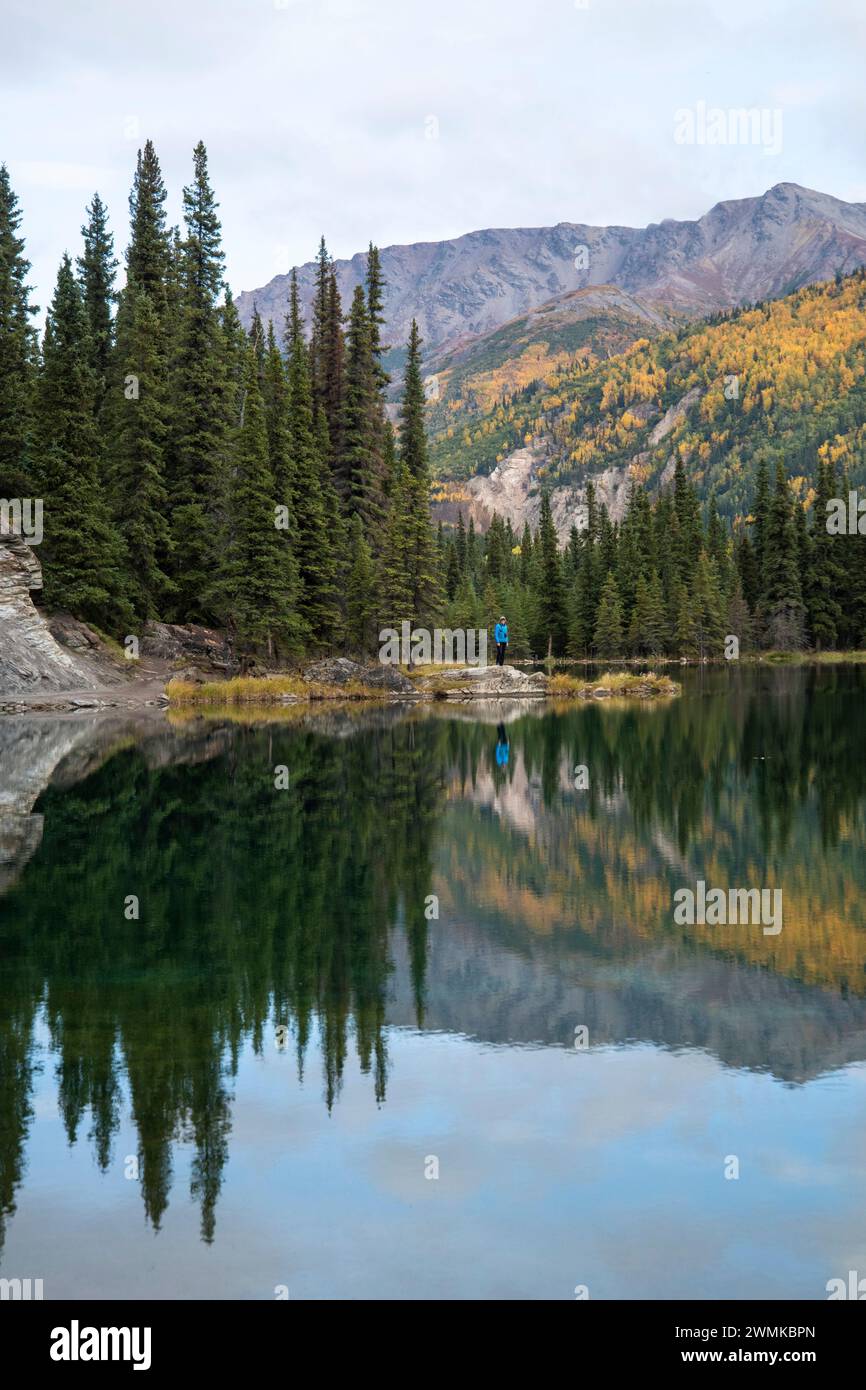 Woman hiking with beautiful reflection of autumn colours along the ...