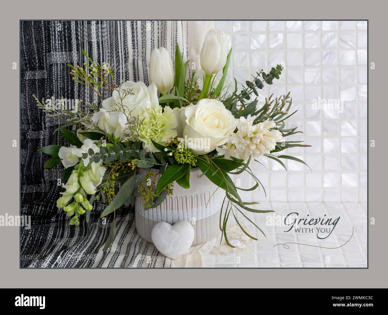 Flower art with a white floral bouquet and caption 'Grieving with you ...