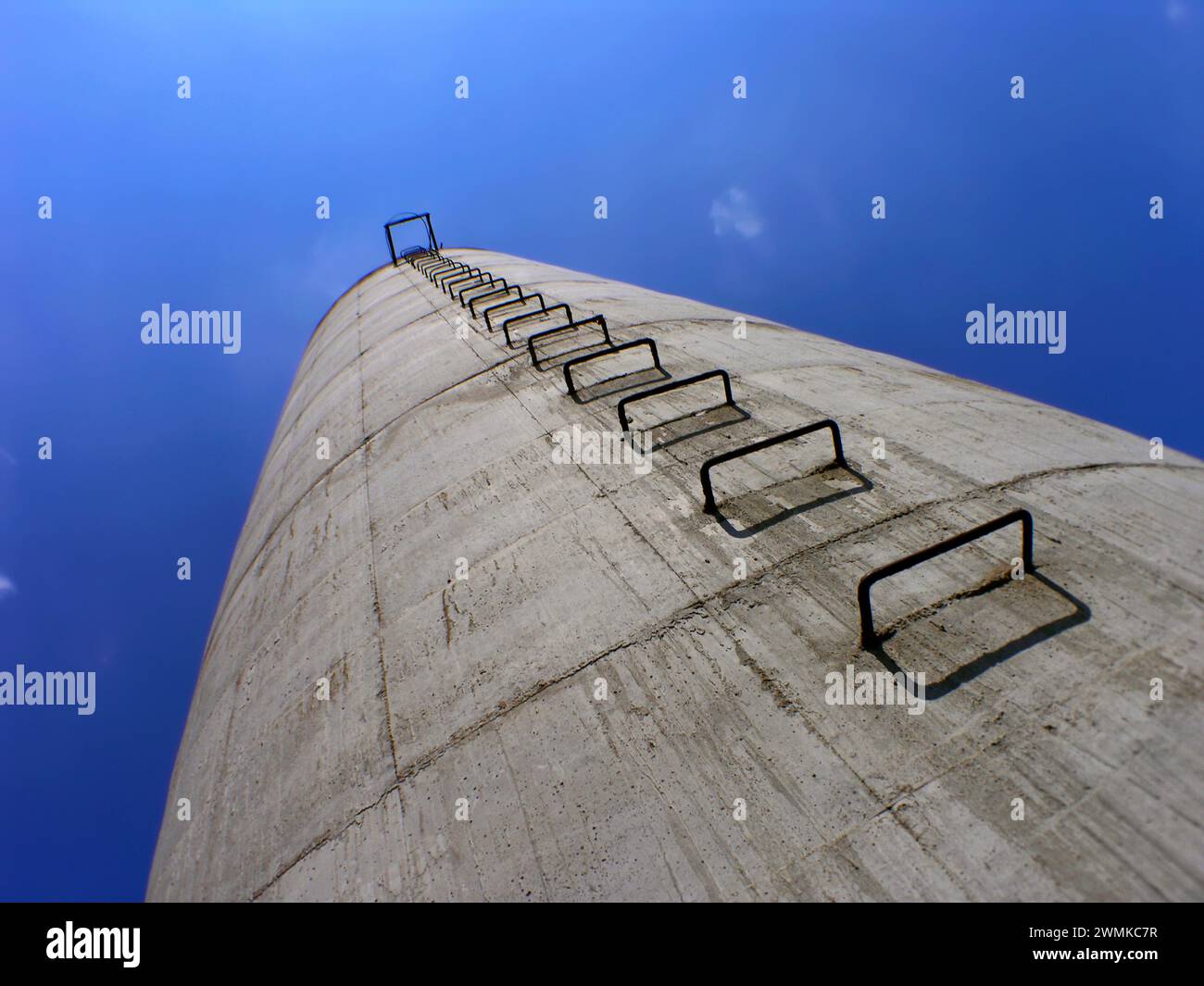 Rusted metal rungs climb skyward, along the length of a concrete silo ...