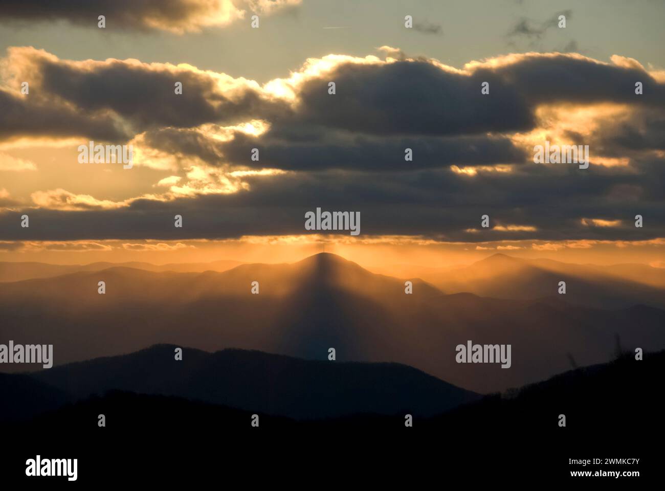 Sunlight streams from behind the grey clouds to light up Mt Pisgah and ...