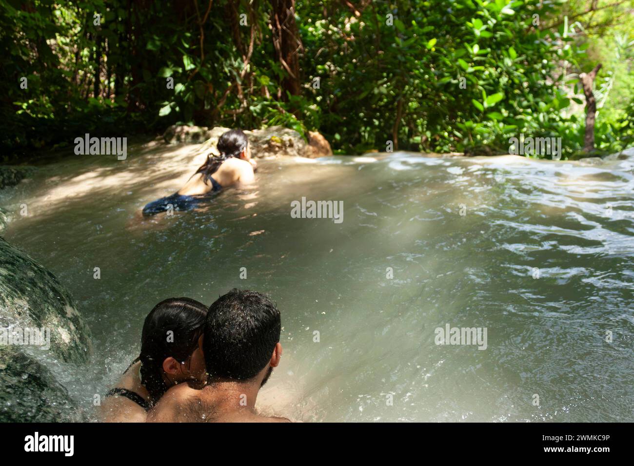 Couple and friend take a water bath in a pit in the middle of ...