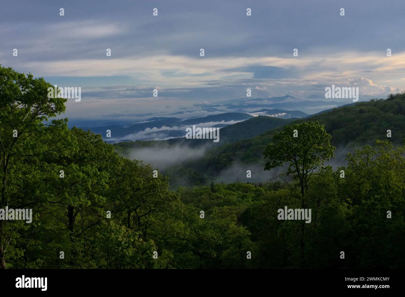Mist rises from the valley after a rain, a vast landscape of mountains ...