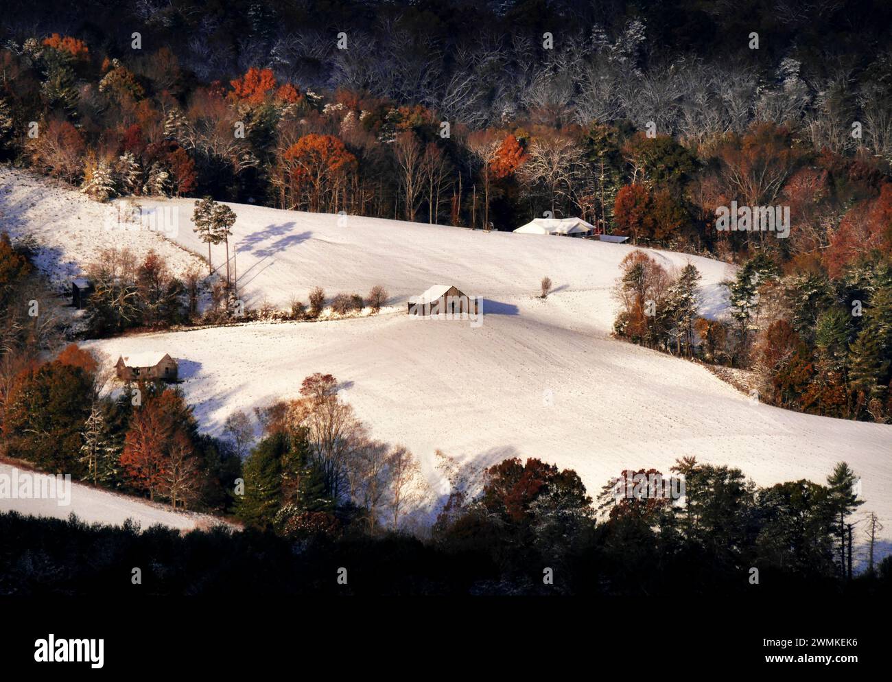 Rustic barn and field are blanketed in white snow and surrounded by trees that are still showing ...