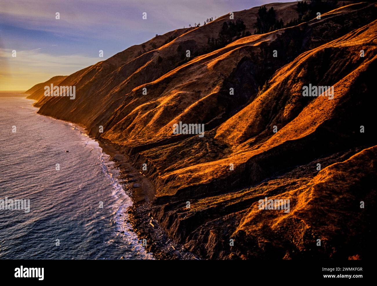Aerial view illuminates eroded slopes above the waves on the coast of ...