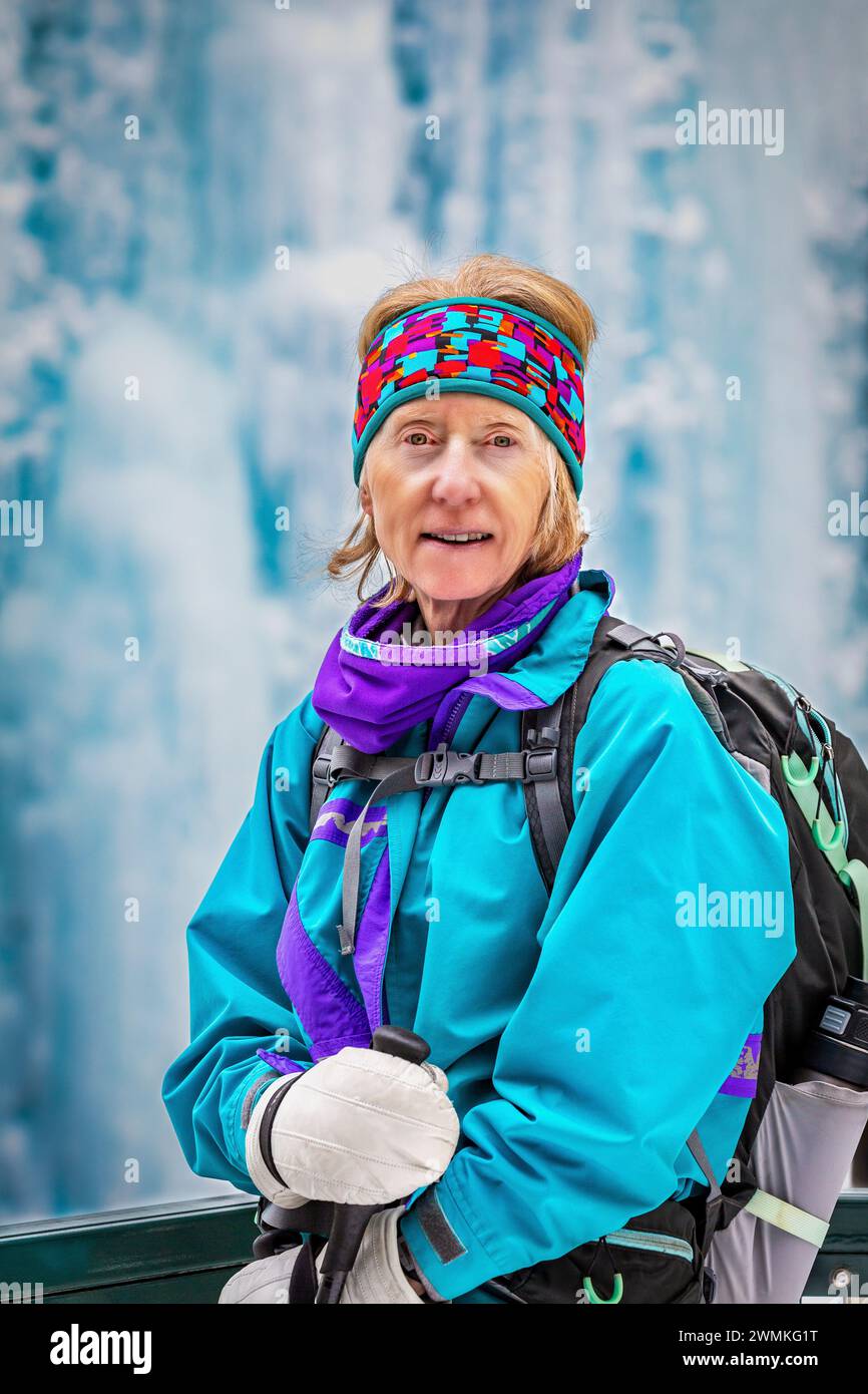 Portrait of a female hiker in the winter with a frozen ice falls in the ...