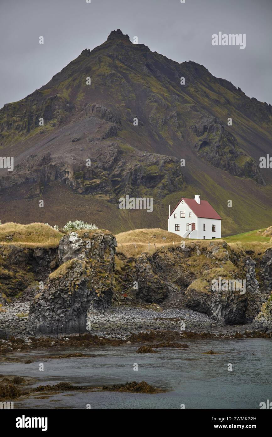 Lone white house and rugged mountain with lava cliffs along the ...