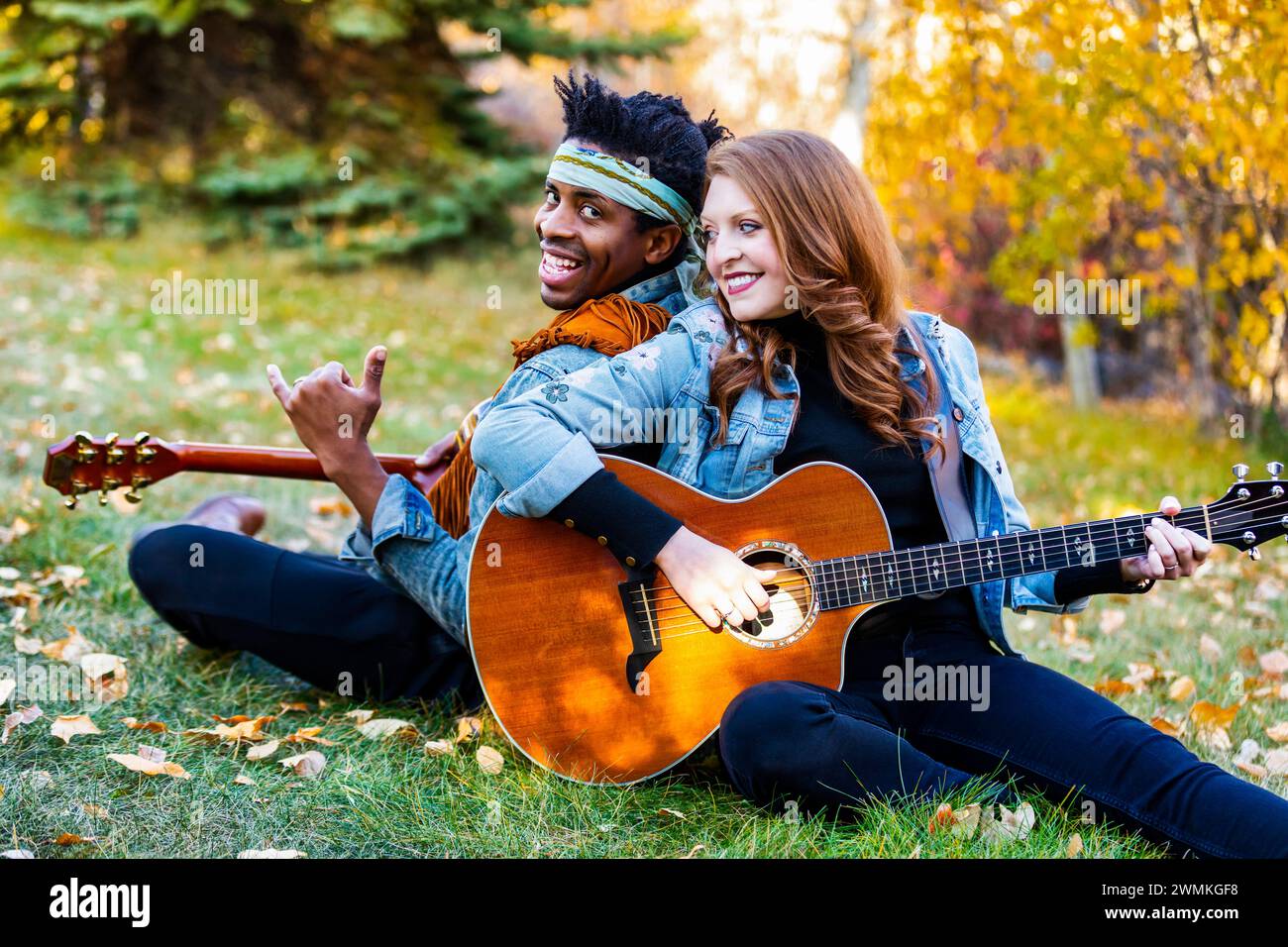 Close Up Portrait Of A Mixed Race Married Couple Sitting On The Grass Back To Back Playing