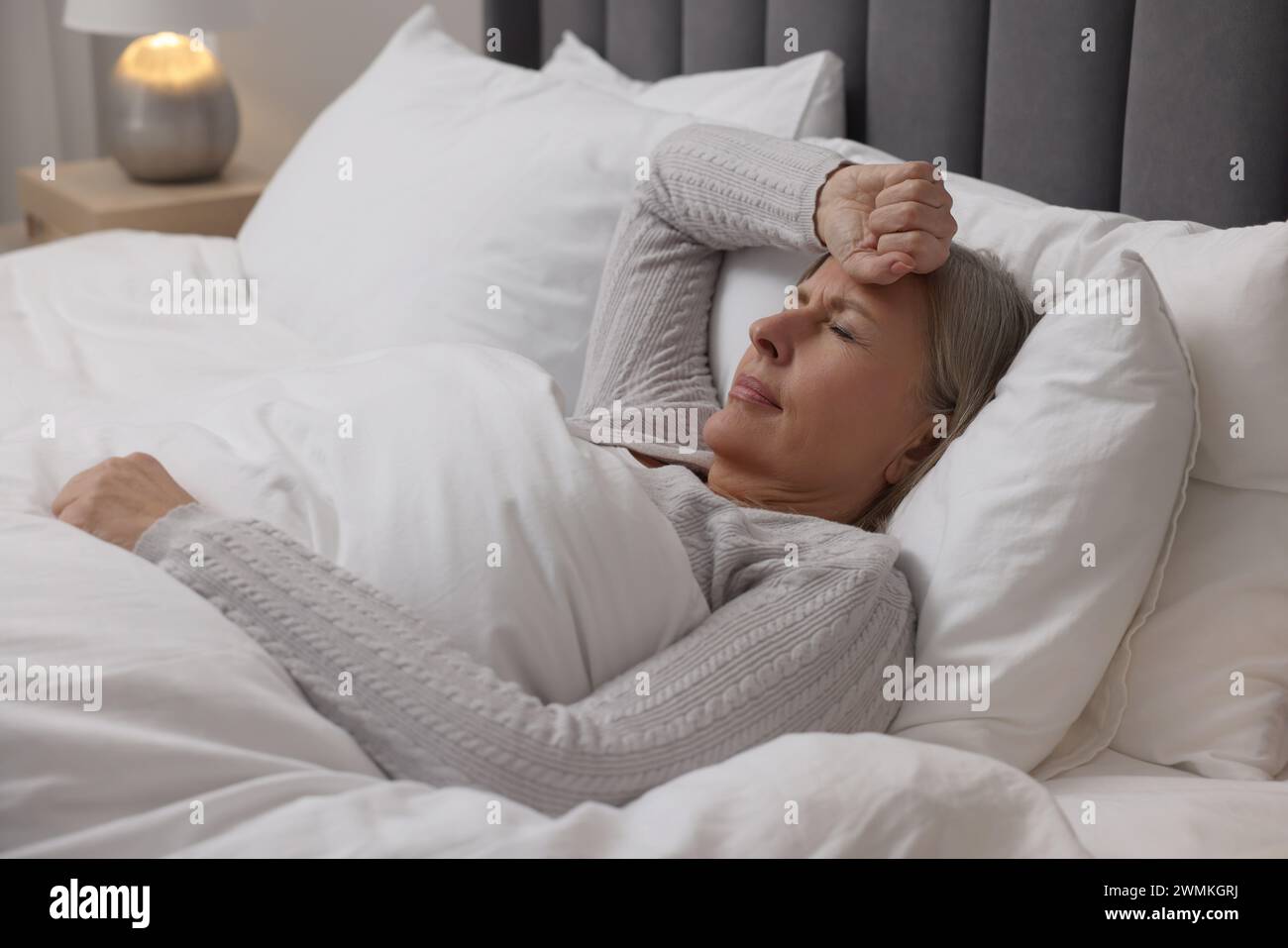 Menopause. Woman suffering from headache in bed Stock Photo - Alamy
