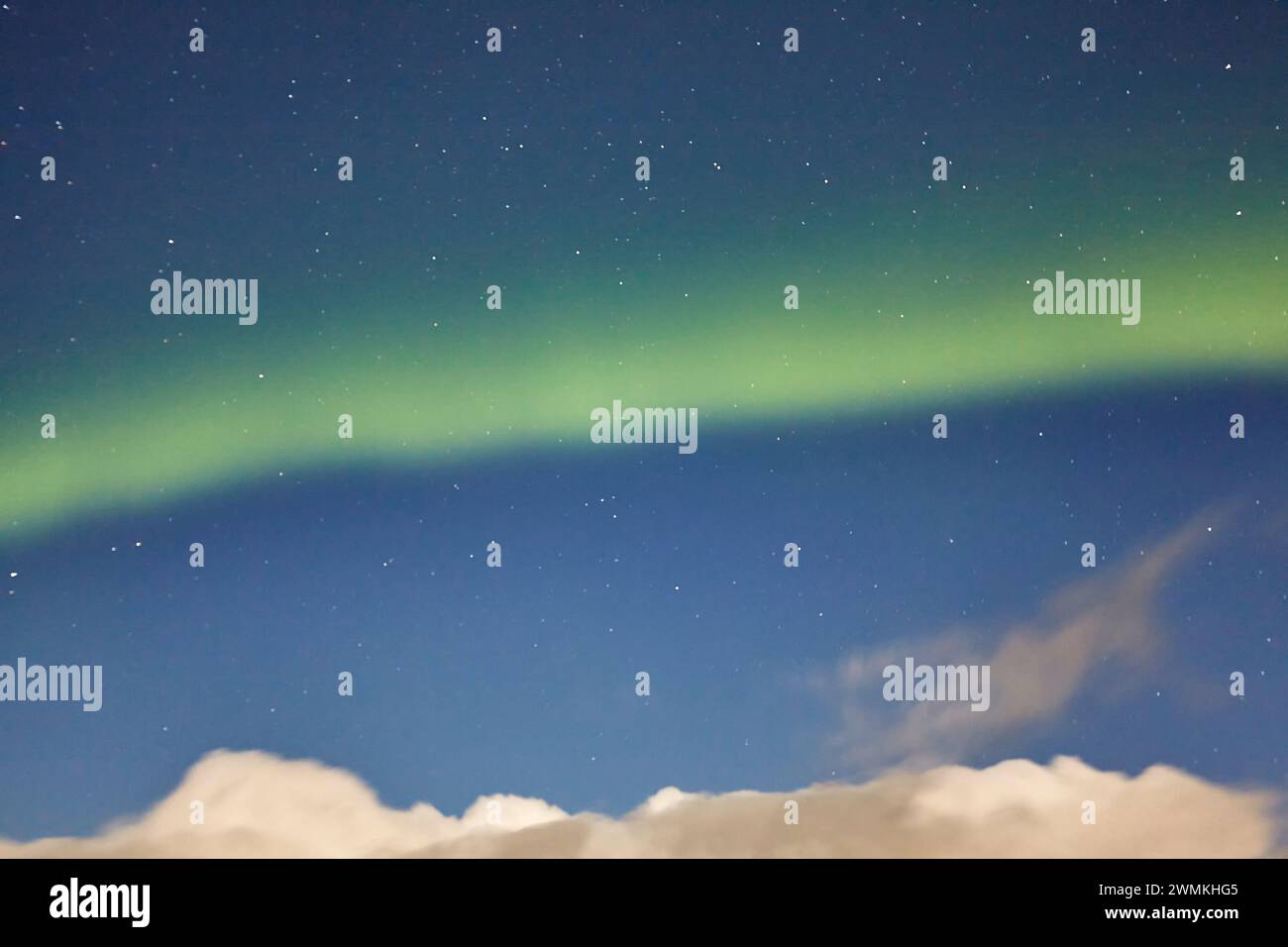 Northern lights in a blue sky filled with stars and a cloud formation ...