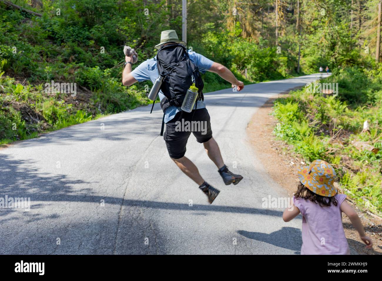 View taken from behind of a father jumping in the air with his daughter ...