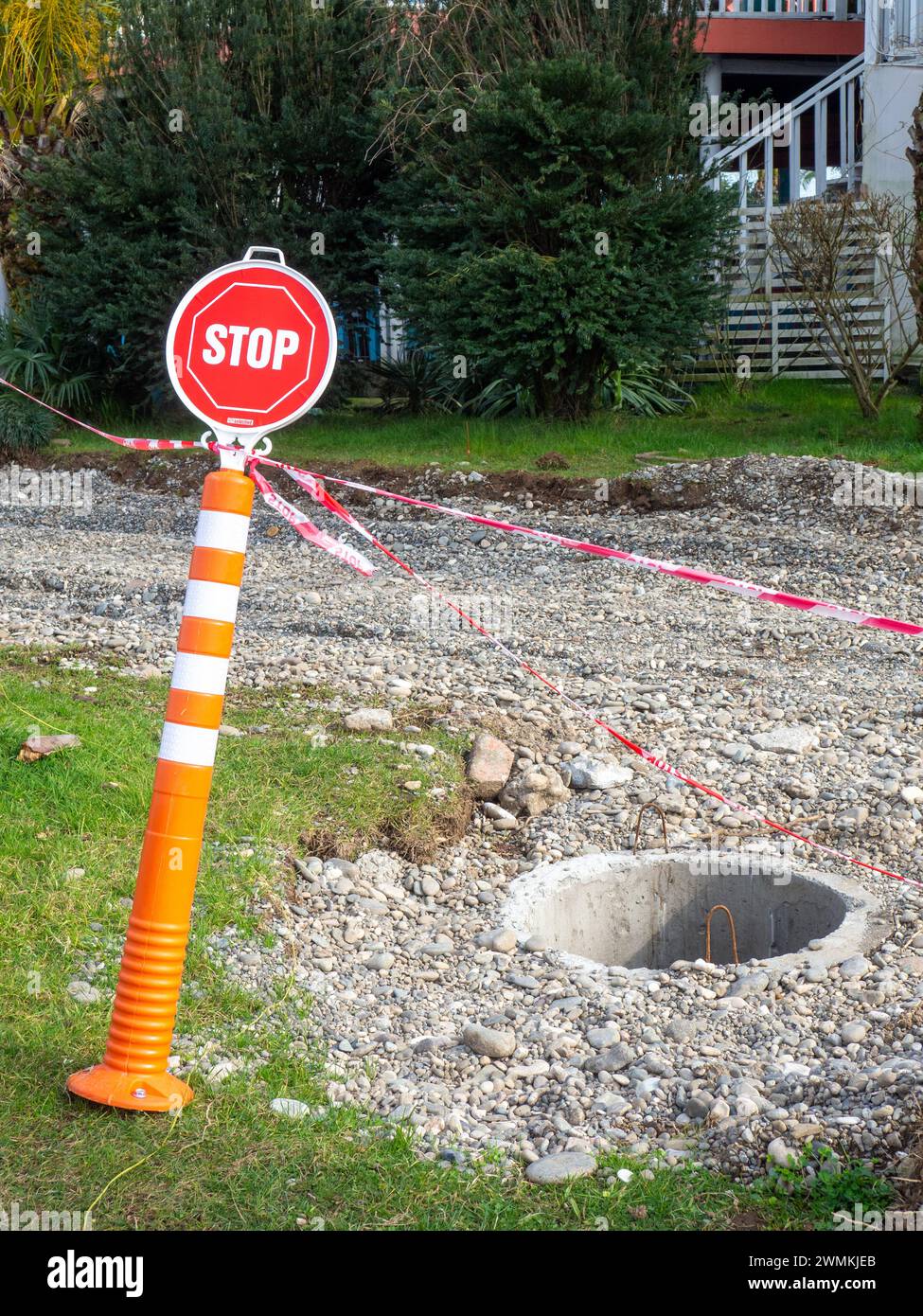 A stop sign in a park in front of an open manhole. Danger lies ahead. A ...