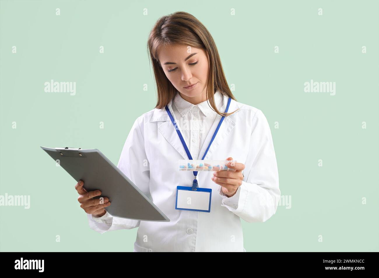 Female doctor with container of vitamin supplements and clipboard on ...