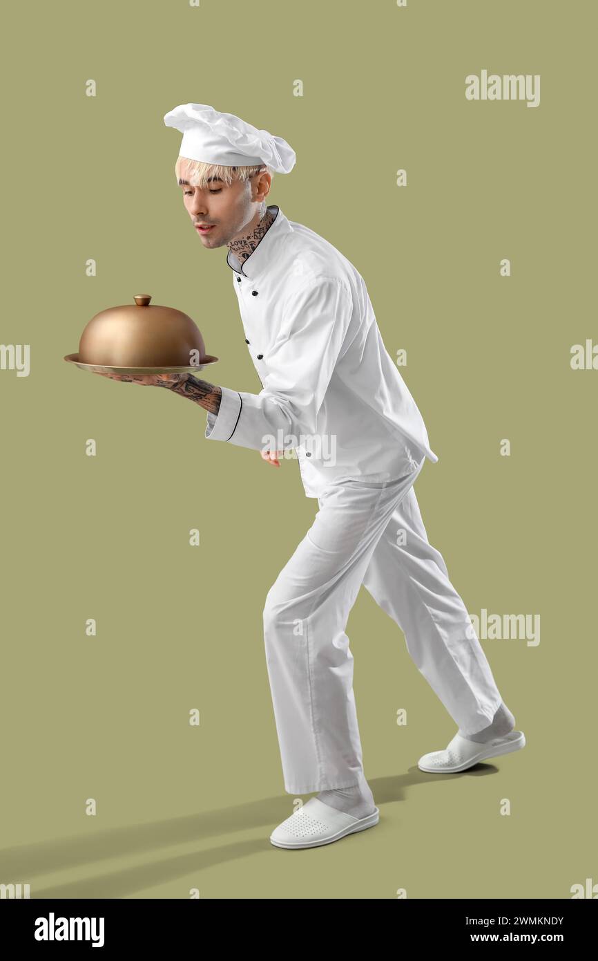 Tattooed male chef with cloche on green background Stock Photo - Alamy