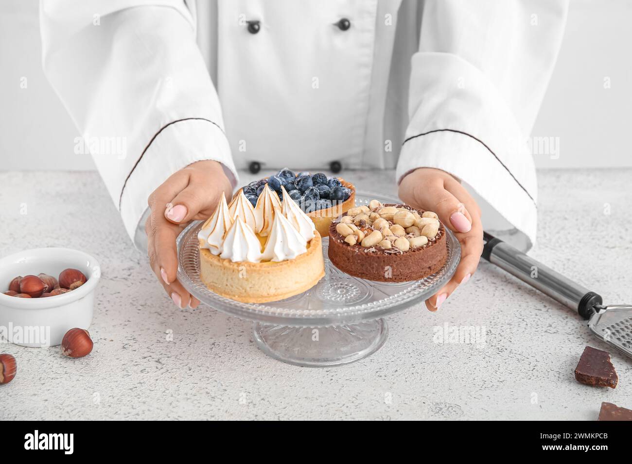 Female confectioner with tasty cakes on white background Stock Photo ...