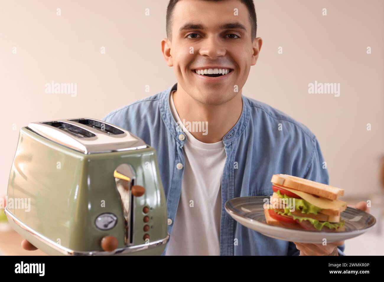 Young man with modern toaster and delicious sandwiches in kitchen Stock ...