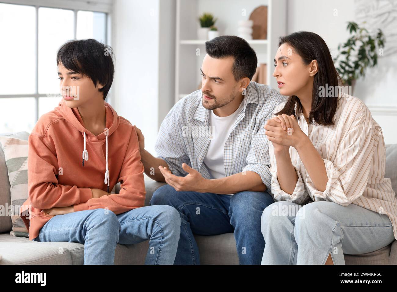 Upset teenage boy with his parents sitting at home. Family problem ...