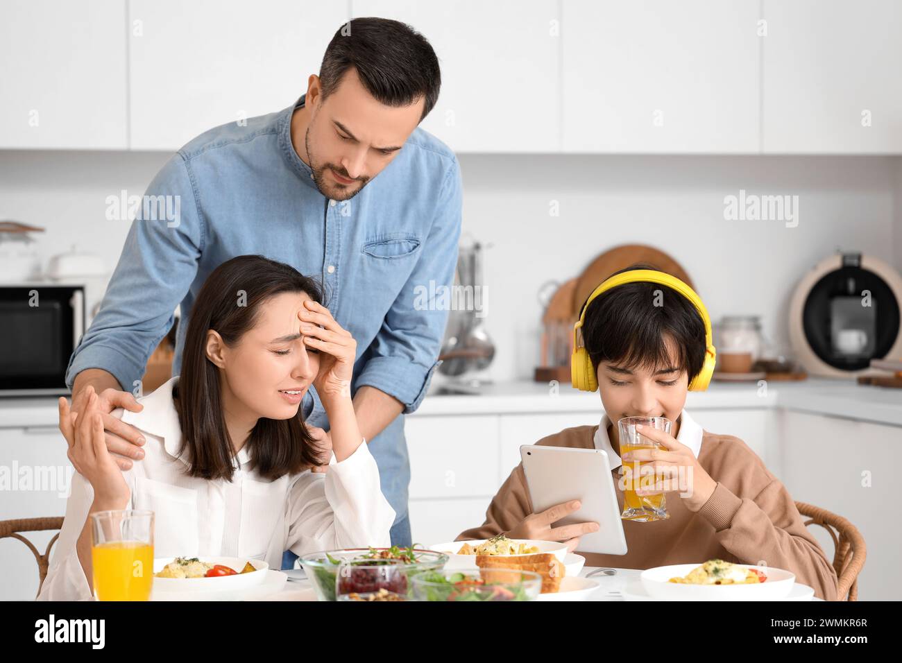 Upset parents with their teenage son at table during dinner in kitchen. Family problem concept ...