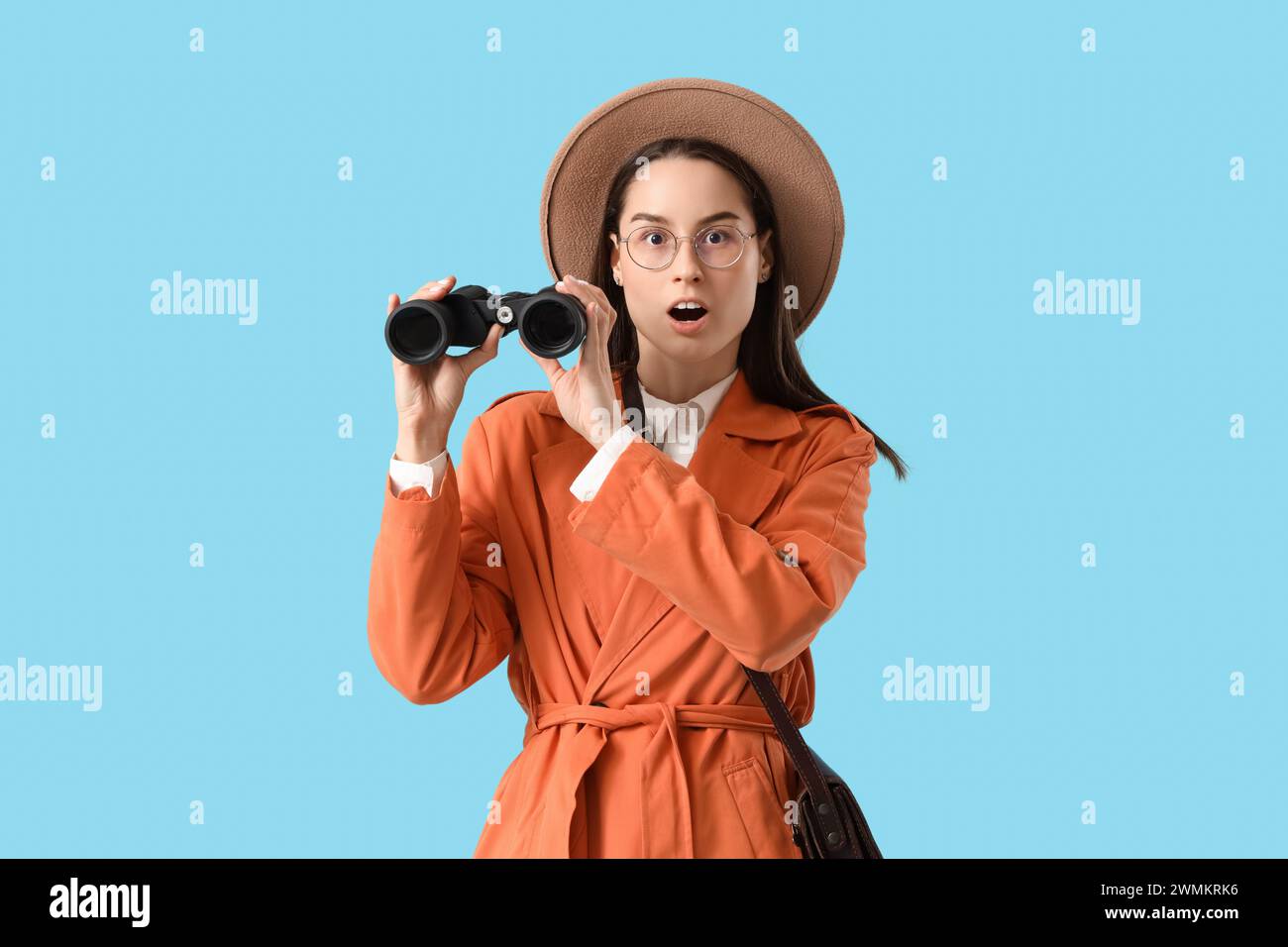 Shocked female detective with binoculars on blue background Stock Photo ...