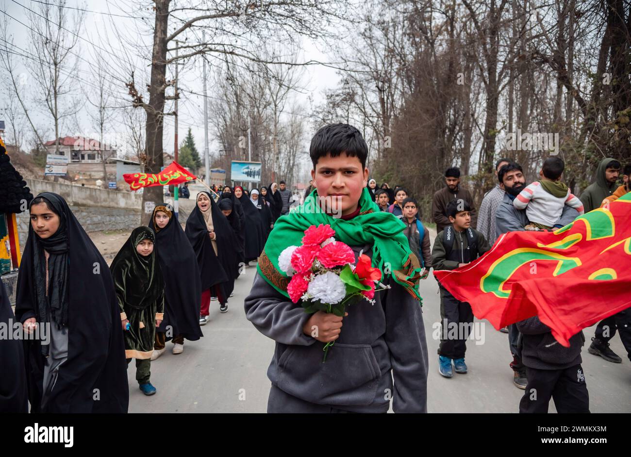 Budgam, India. 26th Feb, 2024. A Kashmiri Shia Muslim holds flowers in ...