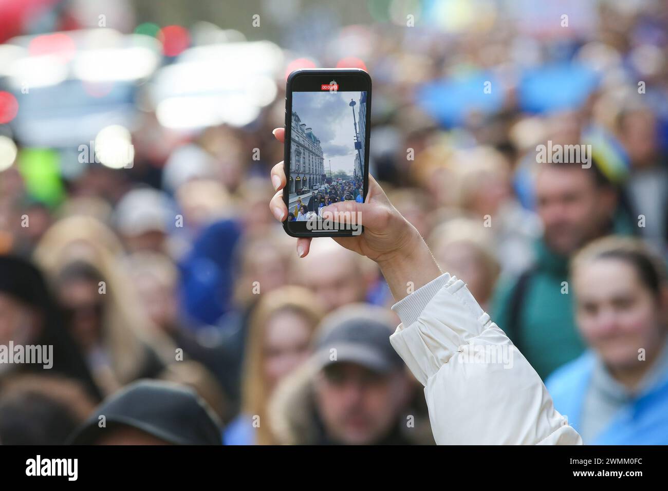 London, UK. 24th Feb, 2024. A woman takes photos using a mobile phone ...