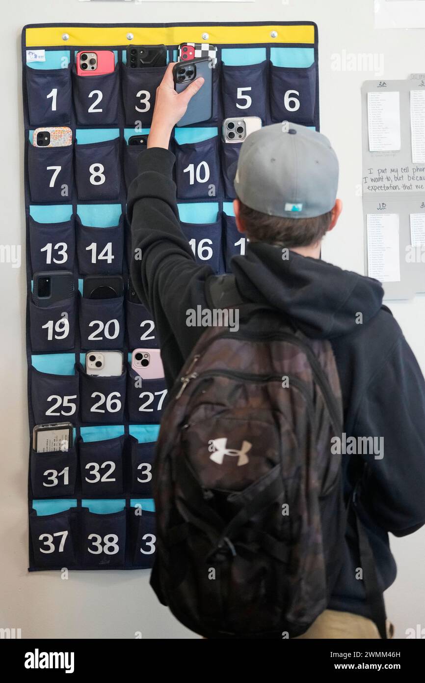 A ninth grader places his cellphone into a phone holder as he enters ...