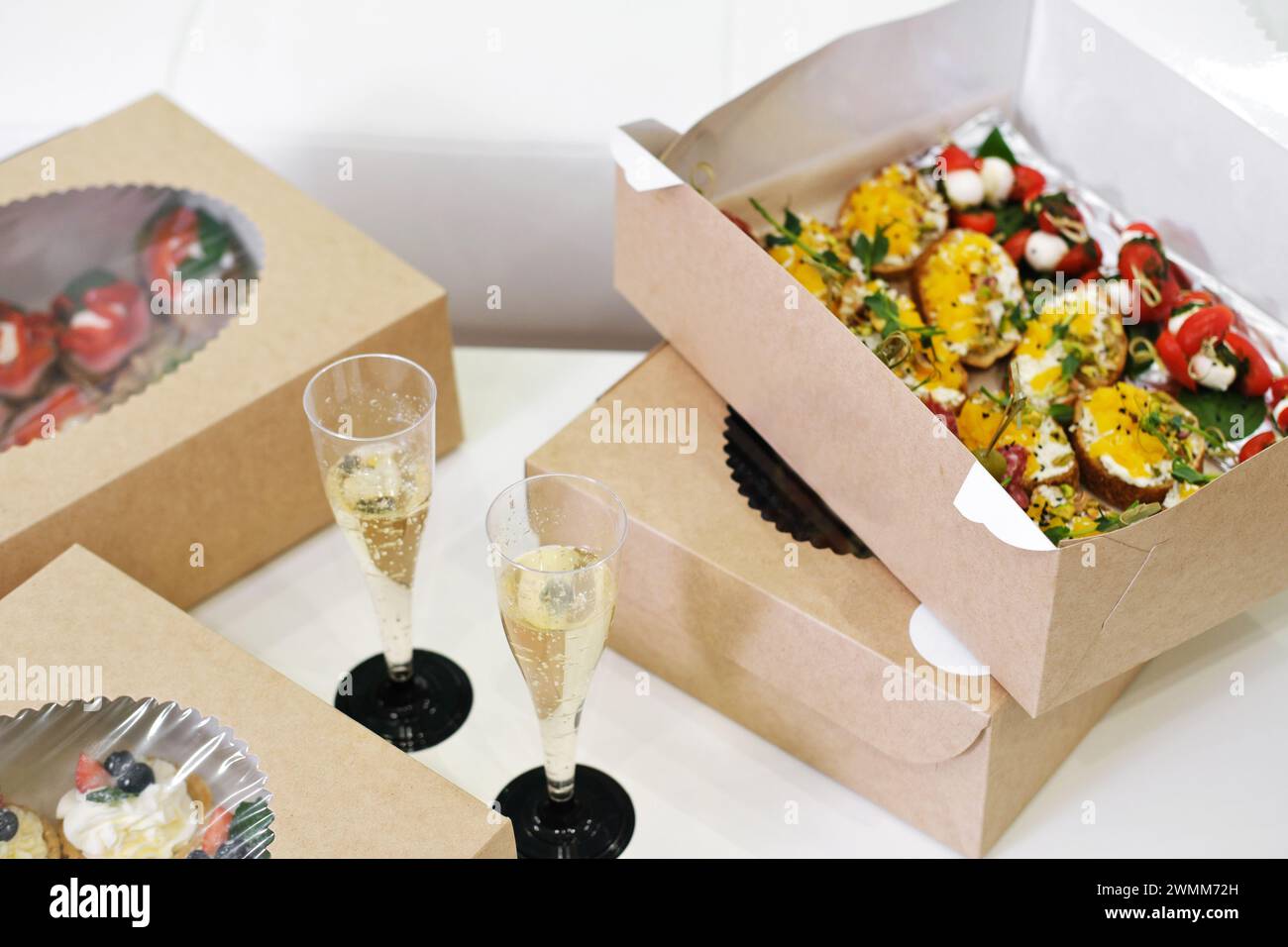 Catering set up on a white table with gourmet snacks in cardboard boxes ...