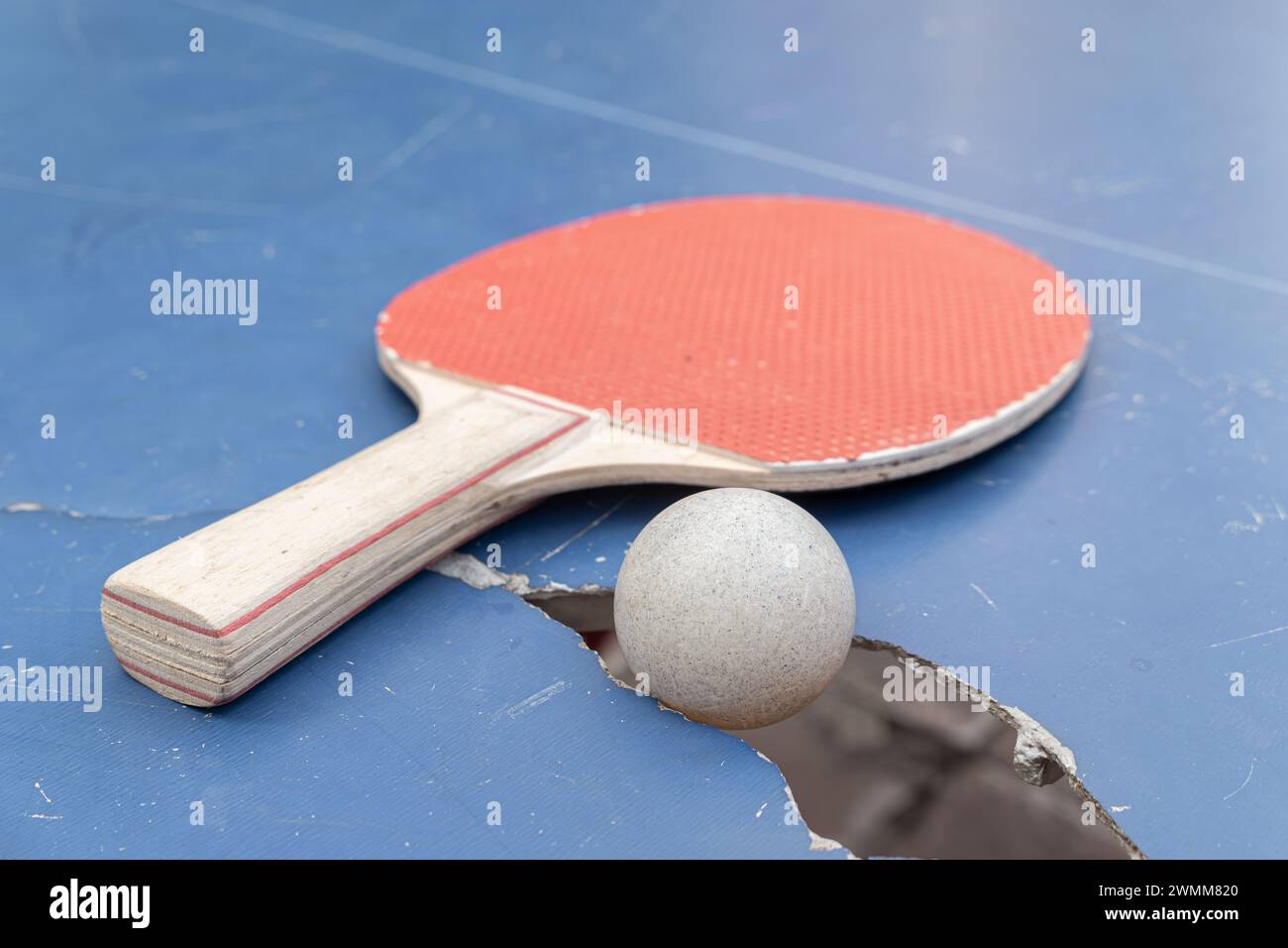 pingpong ball and racket on a damaged table at horizontal composition ...
