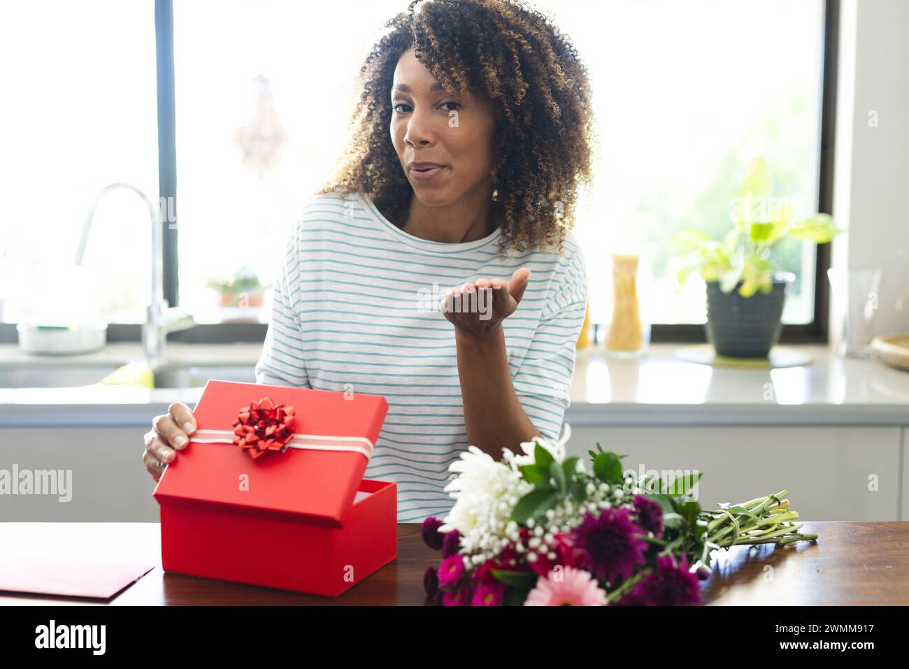 Biracial woman presents a gift at home during an online date video call ...