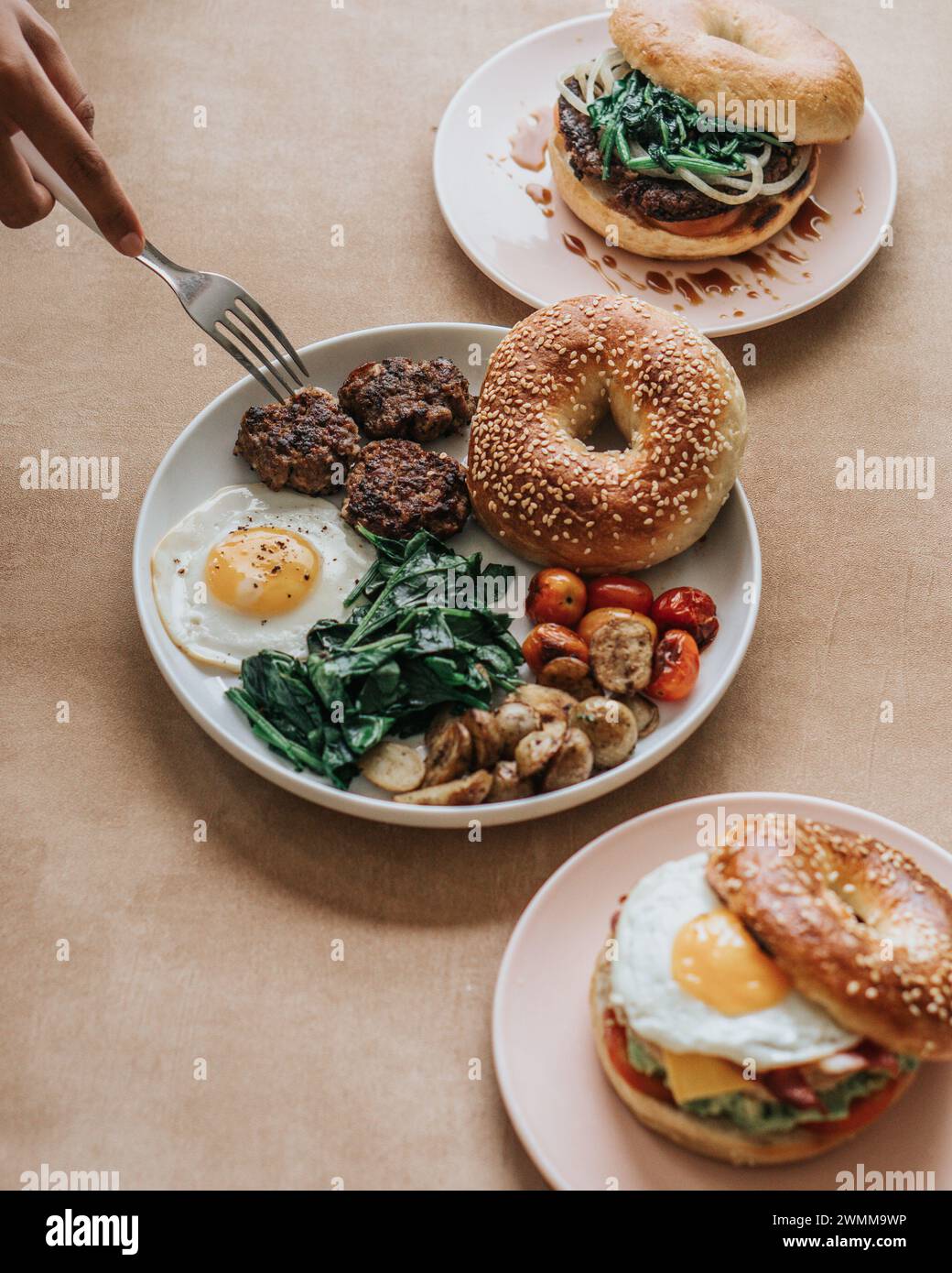 A half-eaten sesame seed bagel, sausage patty, two sunny-side up eggs ...