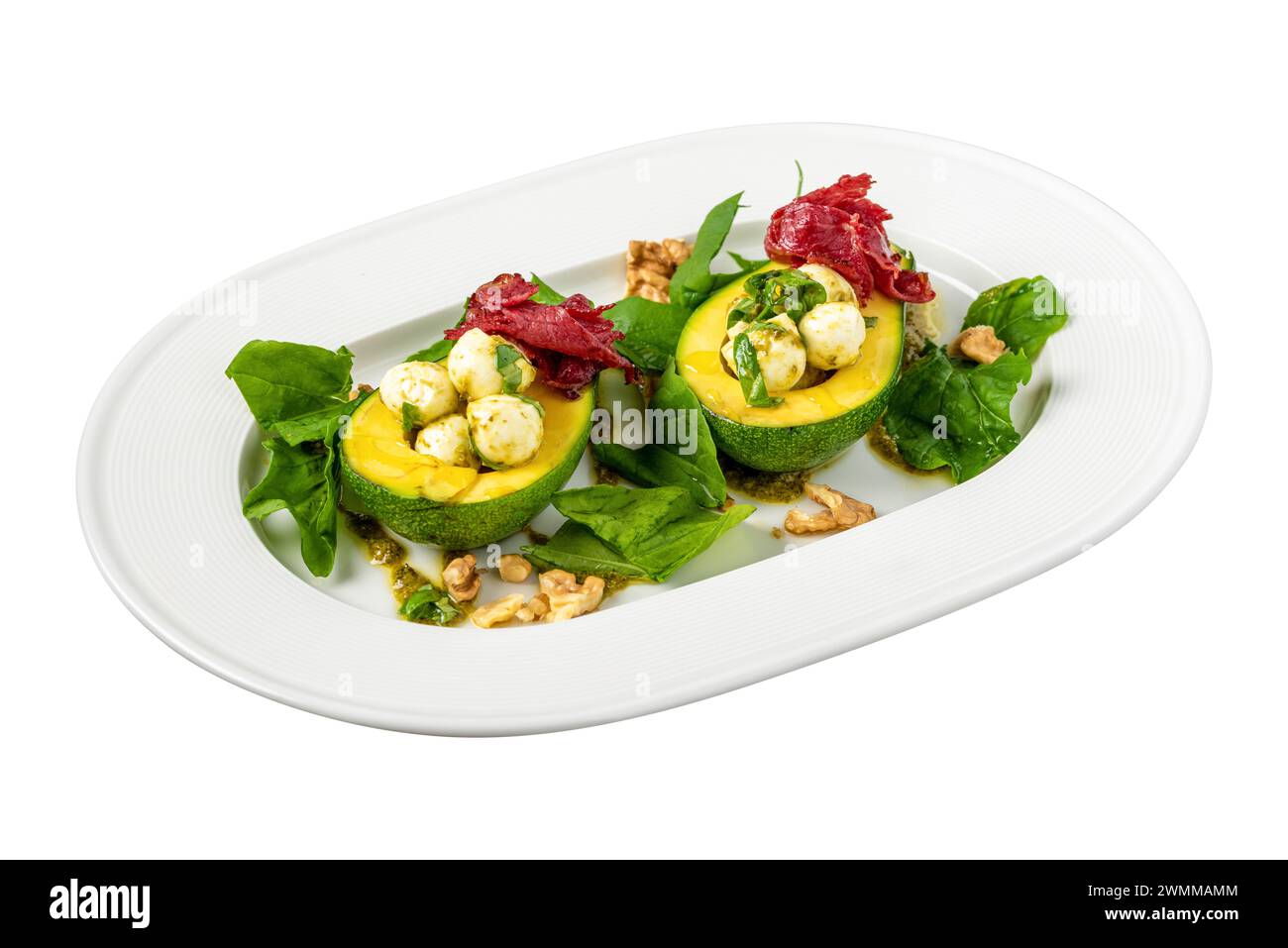 Bocconcini cheese balls in halves of avocado served with salad on white ...