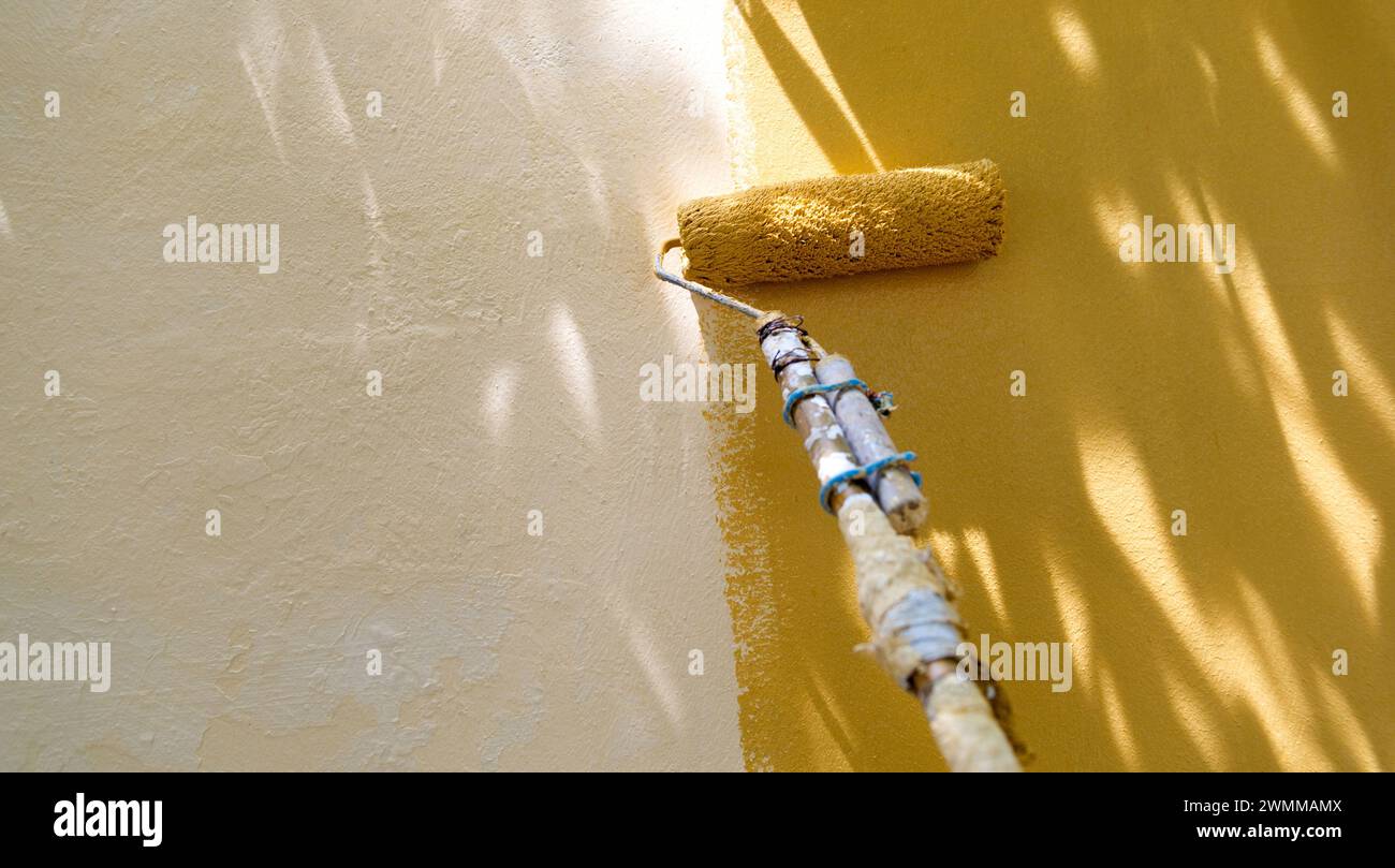 Painting wall with roller and yellow dye Stock Photo - Alamy