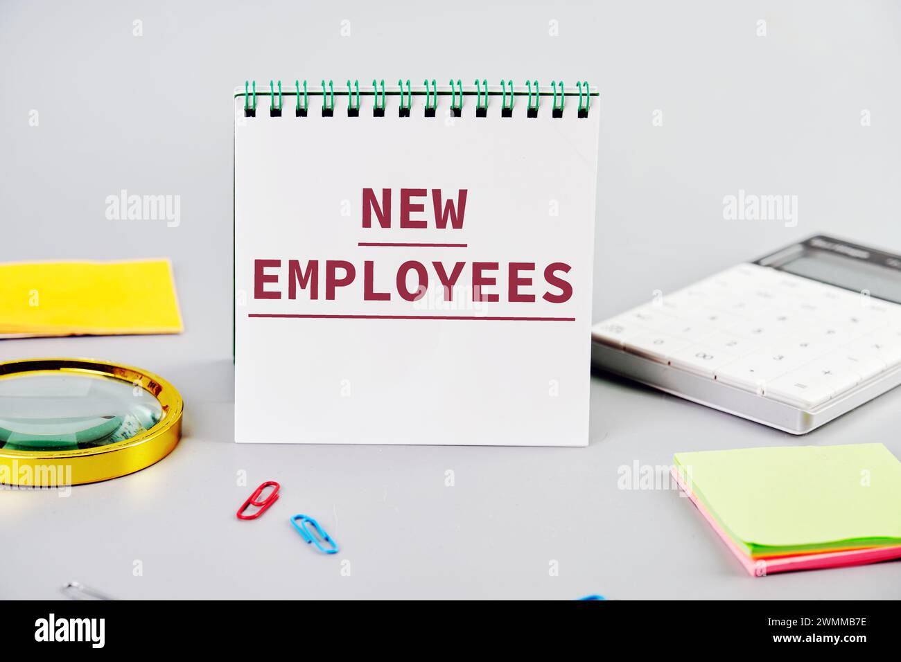 NEW EMPLOYEES Text written on a blank sheet of notepad next to office ...