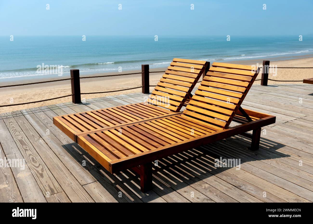 Two wooden beach chairs on a deck overlooking the ocean Stock Photo - Alamy
